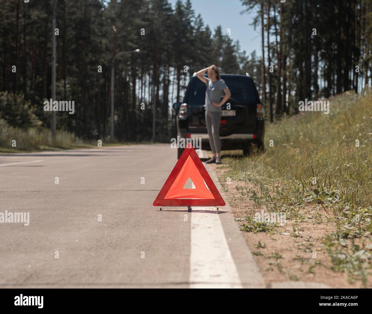 Triangle caution sign on road after car breakdown and driver talking on ...