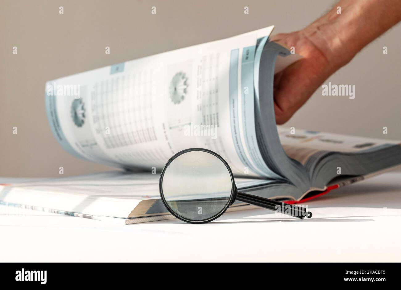 Technical book with turning pages, male hand and magnifier. Engineer ...
