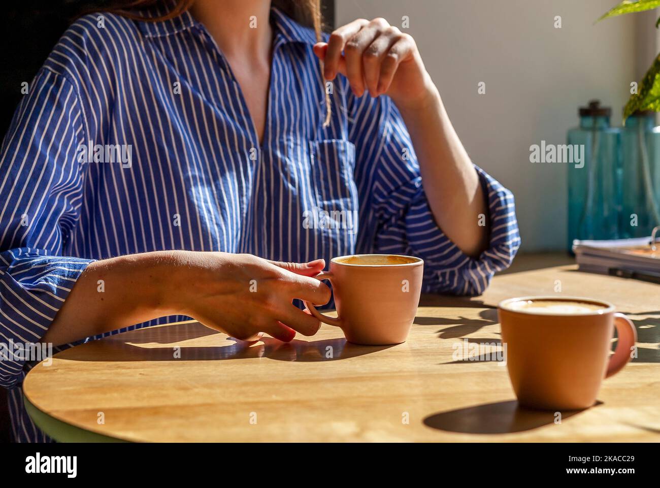 Women hand and coffee cup on wood desk in coffee shop or cafe, close up ...