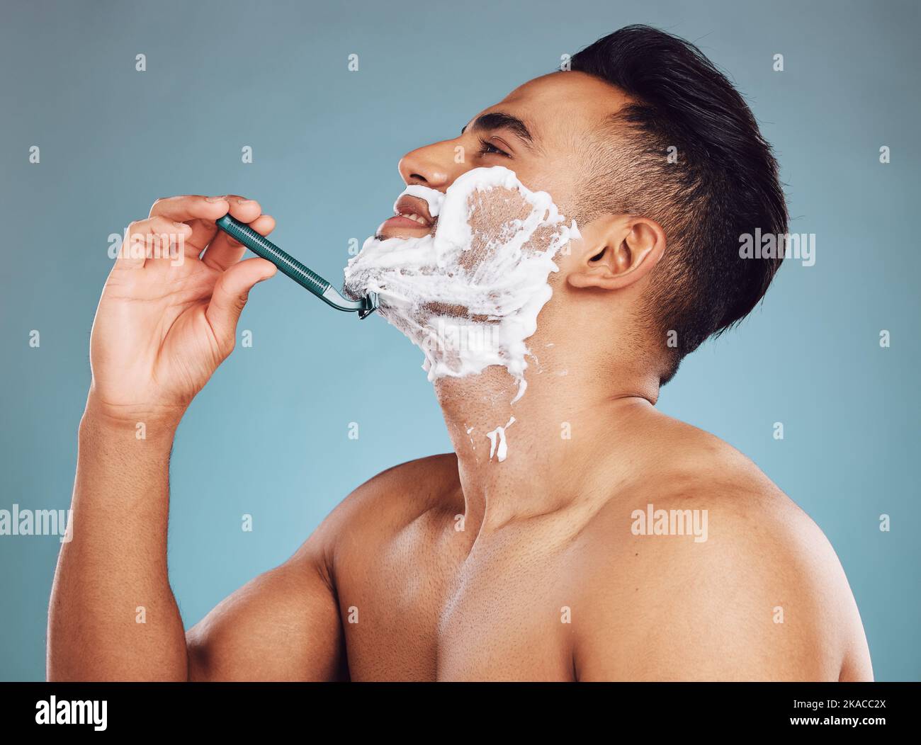 Studio, skincare and man shaving his beard in a daily morning grooming routine with a razor in ...