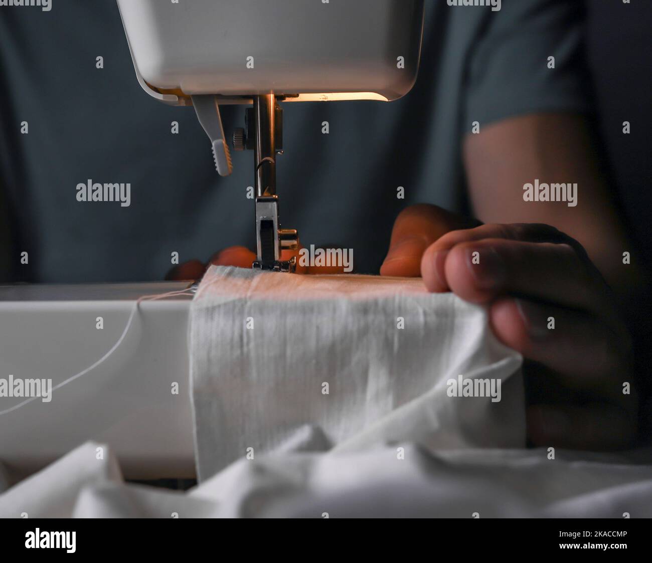 Male hands with cotton cloth at sewing machine during work process ...