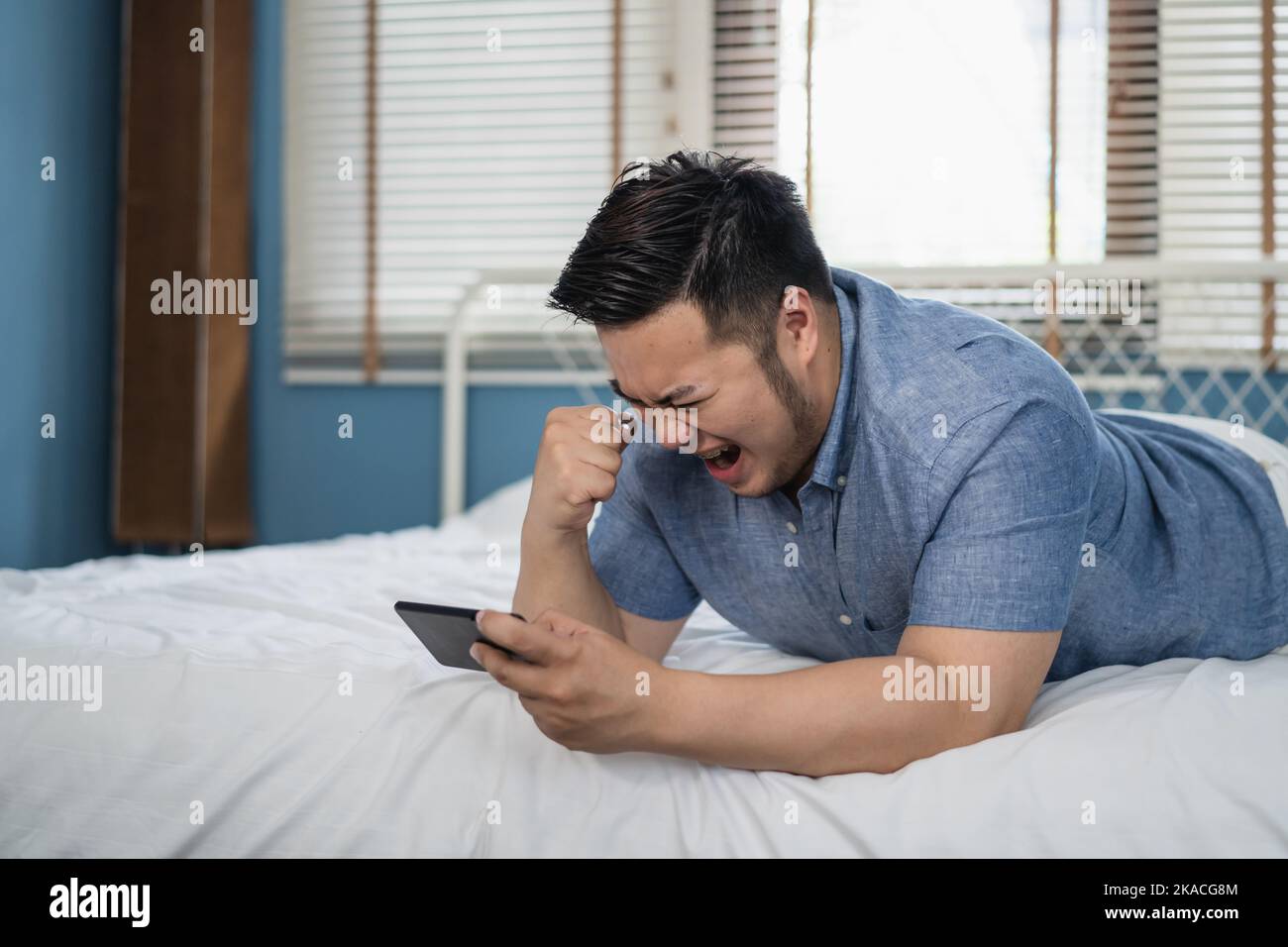 Young Asian plus size man playing a video game on mobile phone and ...