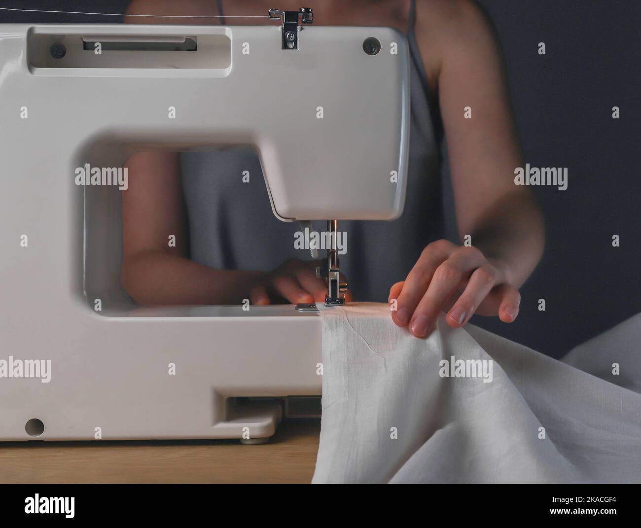 Seamstress hands with linen cloth at sewing machine, working process ...