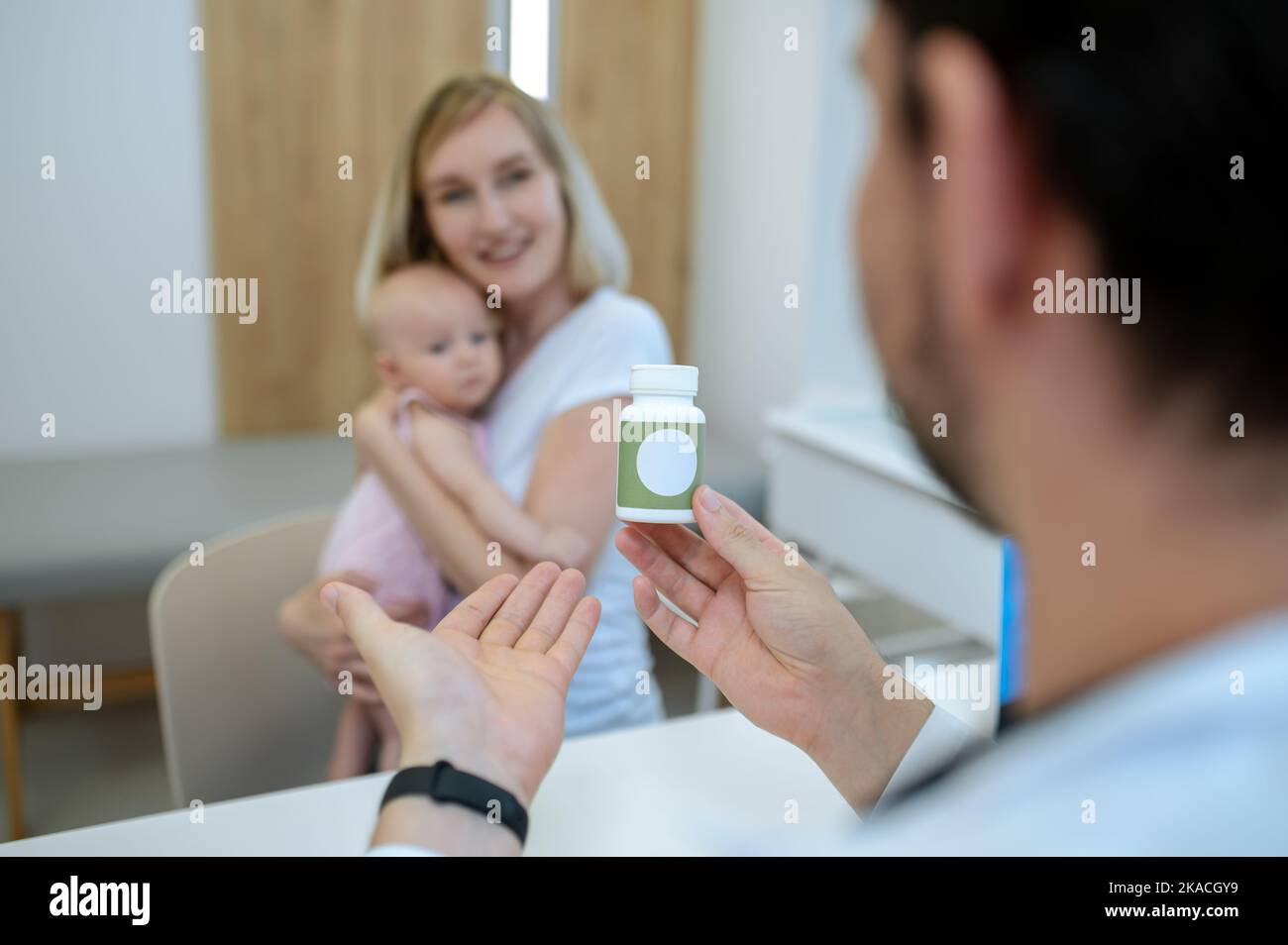 Pediatrician after check up prescribing vitamins to a young mom with a ...