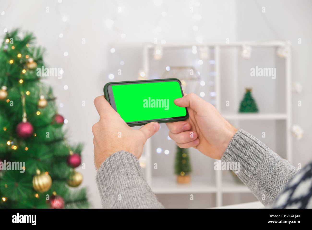 A man holds a phone in a horizontal position with a green screen. Phone ...