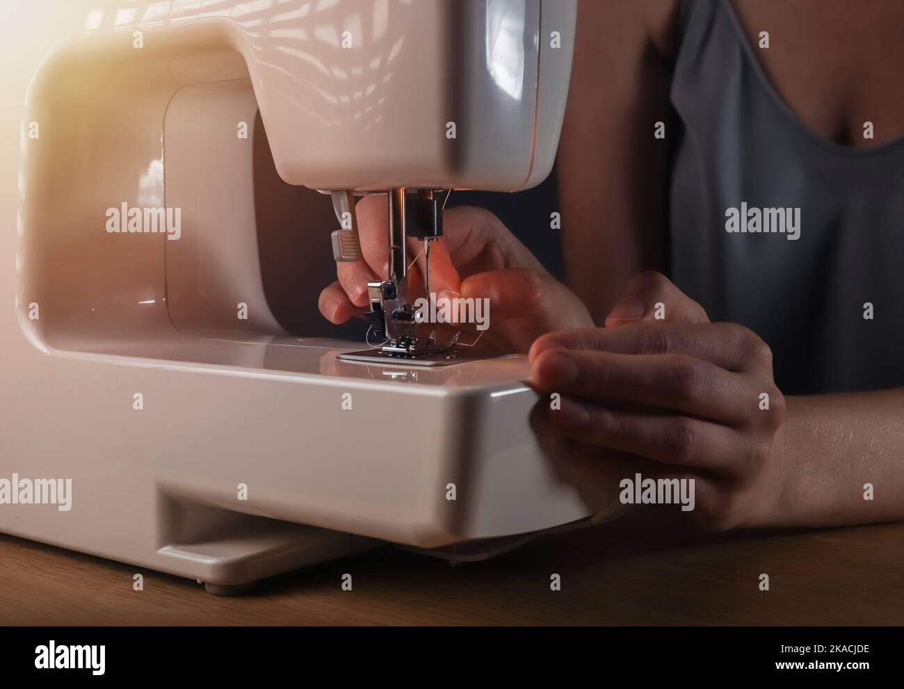 Hands inserting thread through needle hole in sewing machine, details ...