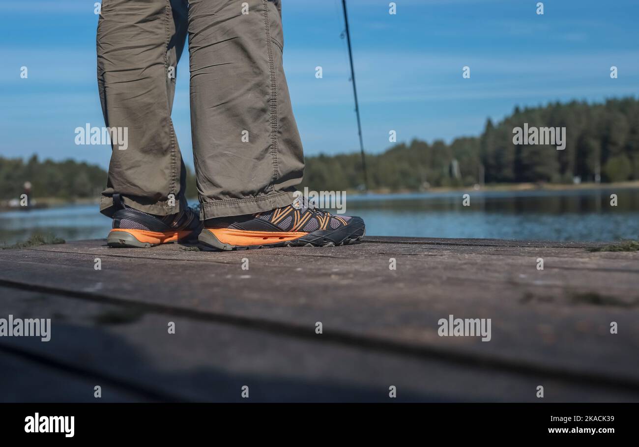 Fishermans legs on wood pier or jetty while fishing Stock Photo - Alamy