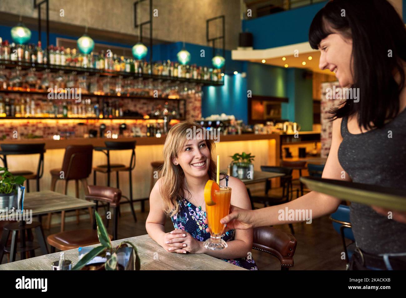 She loves making customers happy. a young waitress serving a drink to a ...