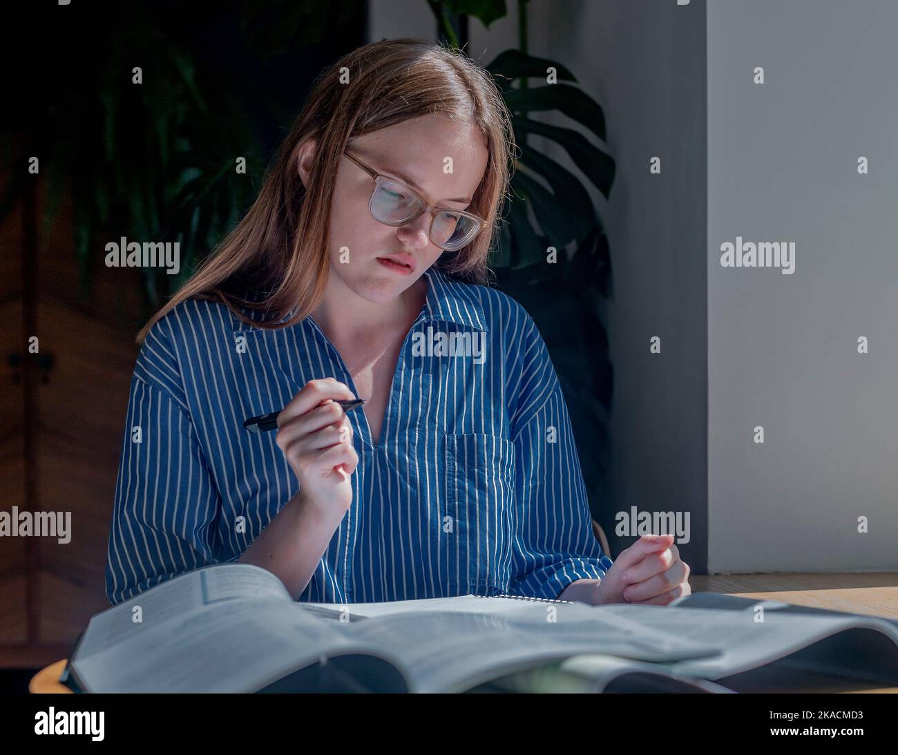 Young woman in eyeglasses thinking, reading, preparing for exams with ...