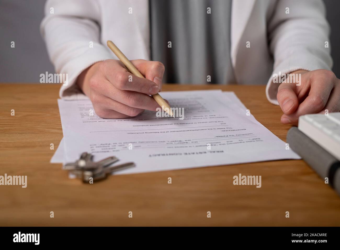 Property keys on desk with real estate contract and agent signing ...