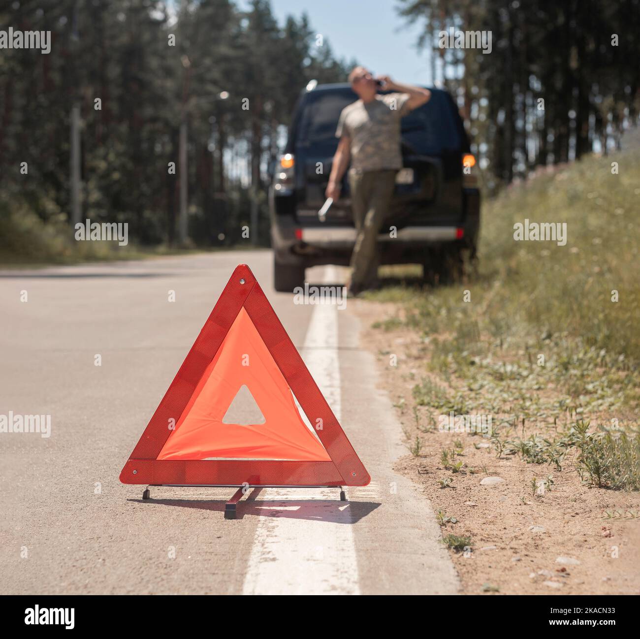 Red triangle caution sign on road after car break down and blurred ...