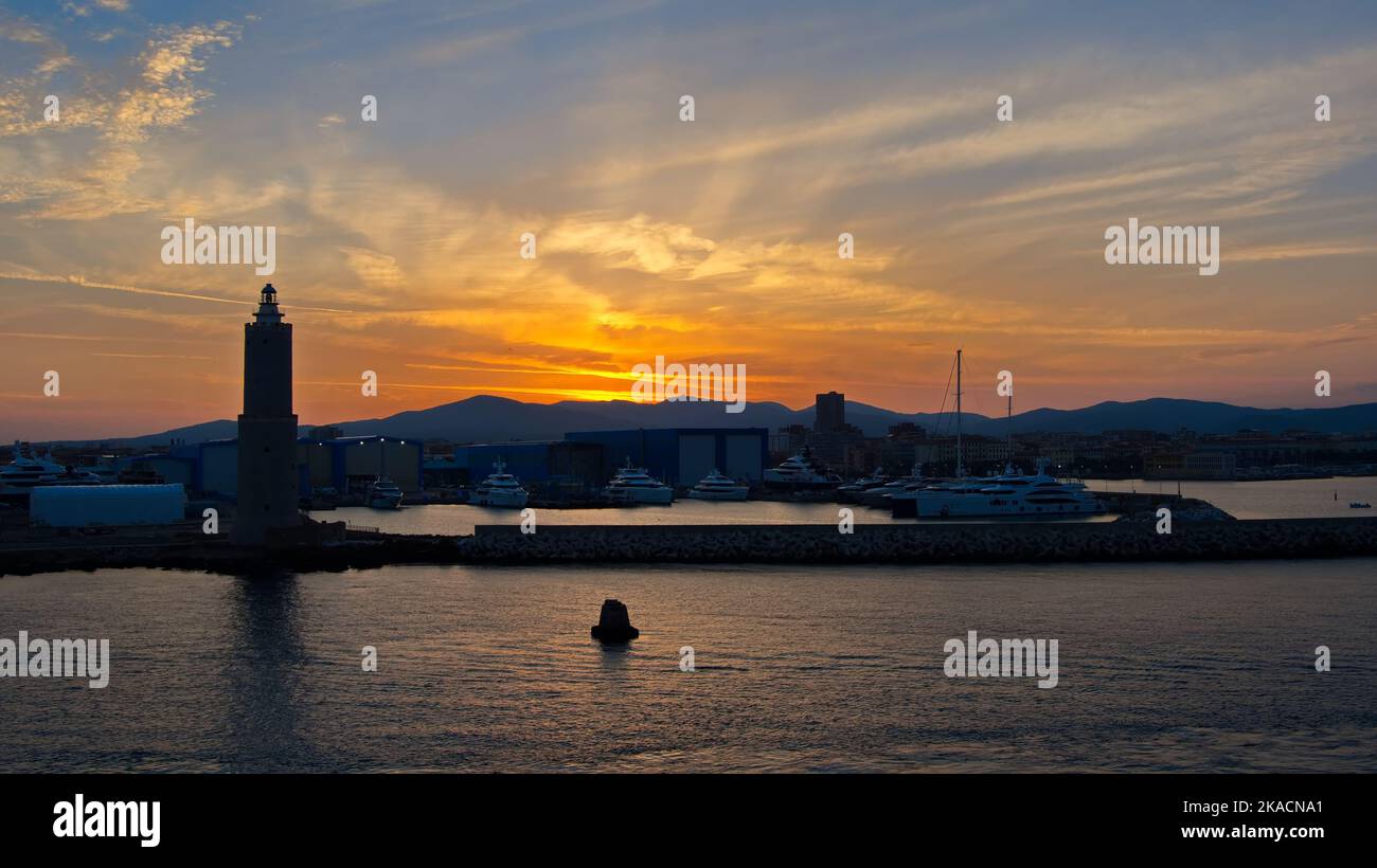 Orange sunset over Lighthouse on the approach to Pisa port Stock Photo ...