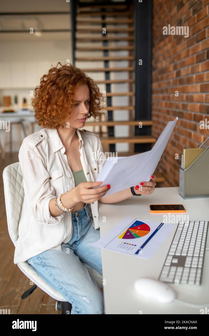 Female manager scrutinizing papers and looking involved Stock Photo - Alamy