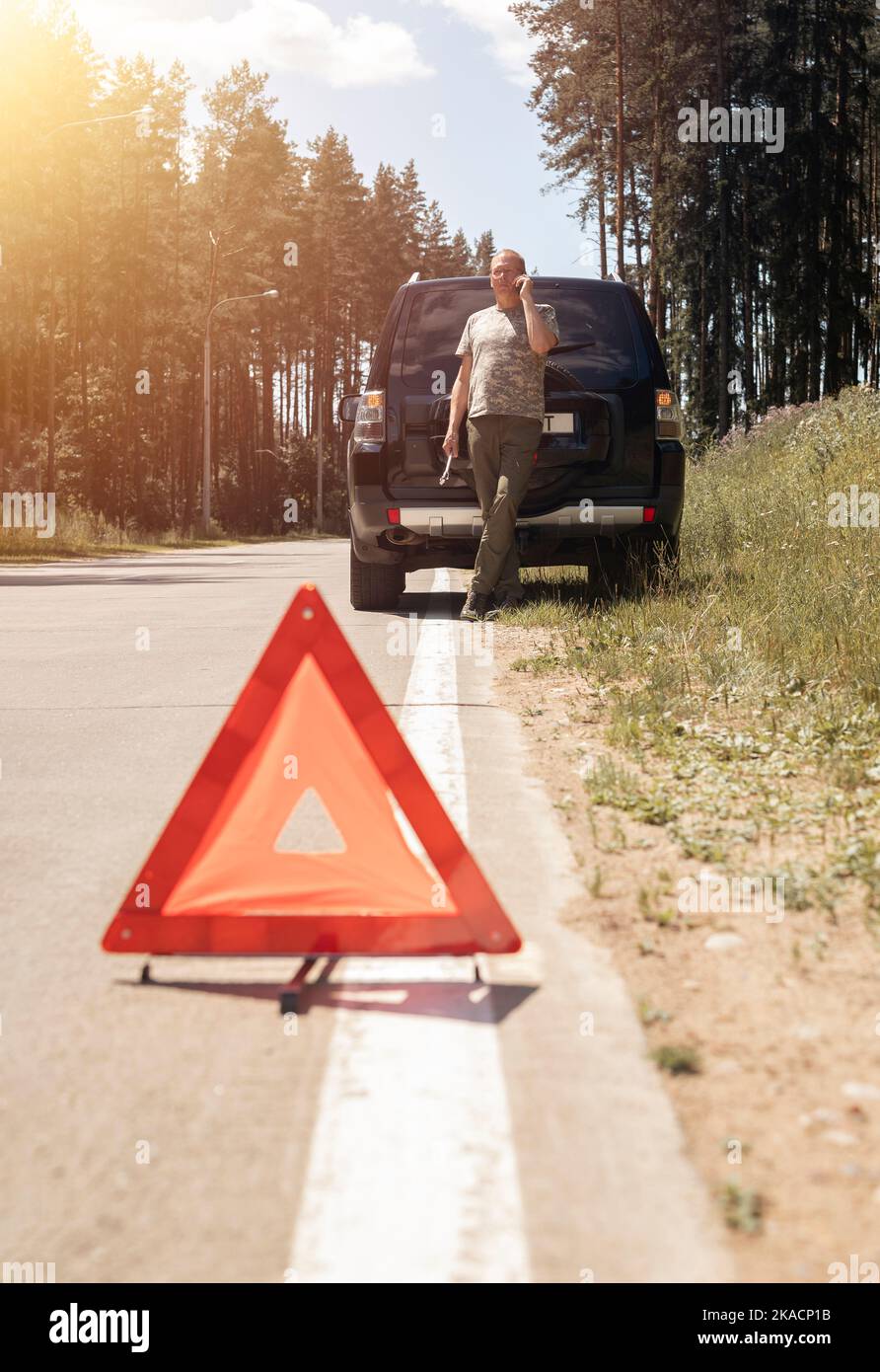Red triangle caution sign on road after car break in road trip and ...