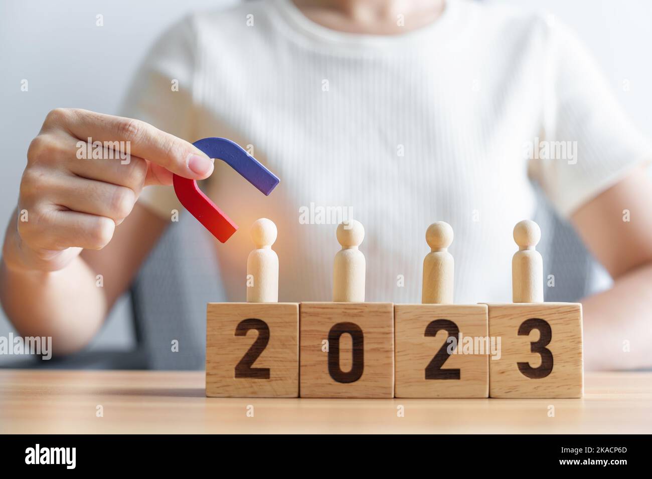 hand holding magnet and pulling man wooden figure from the crowd ...
