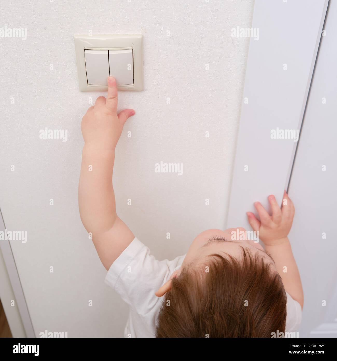 Toddler baby reaches for the light switch, child hand turns on the lamp ...