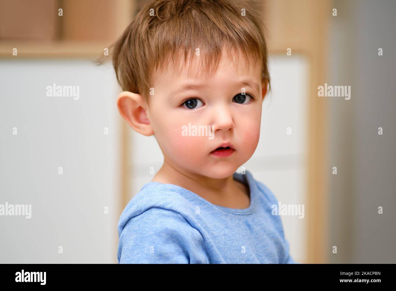Portrait of a thoughtful toddler baby boy on the background of a home ...