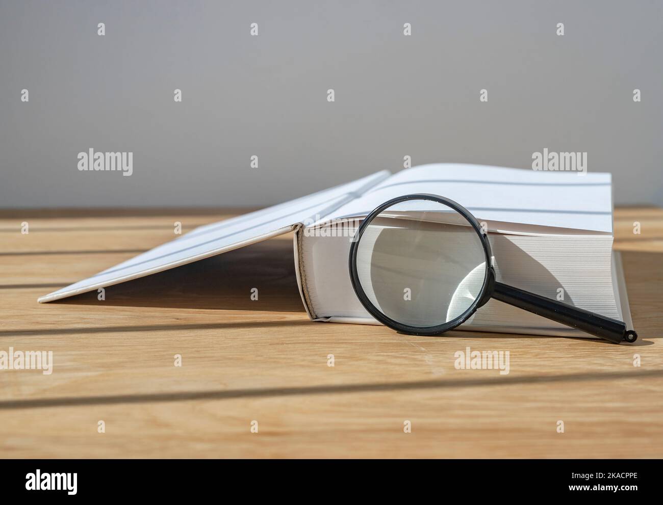 Magnifying lens with open thick book on wood desk with day light Stock ...