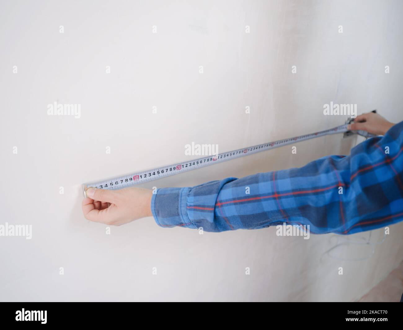 Side view of serious man using measuring tape in room with underfloor ...