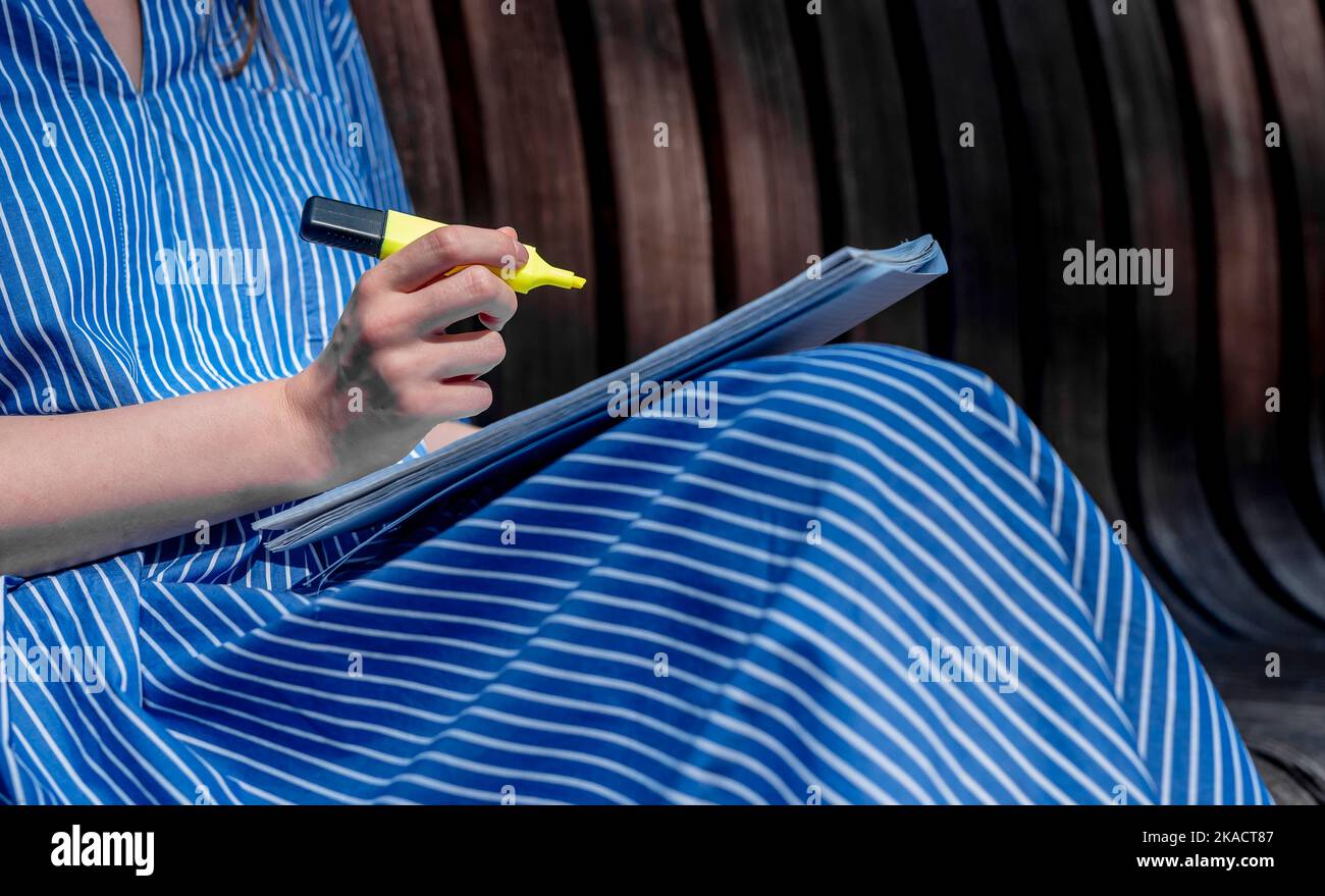 Female hands taking notes close up, sitting on bench in park with ...