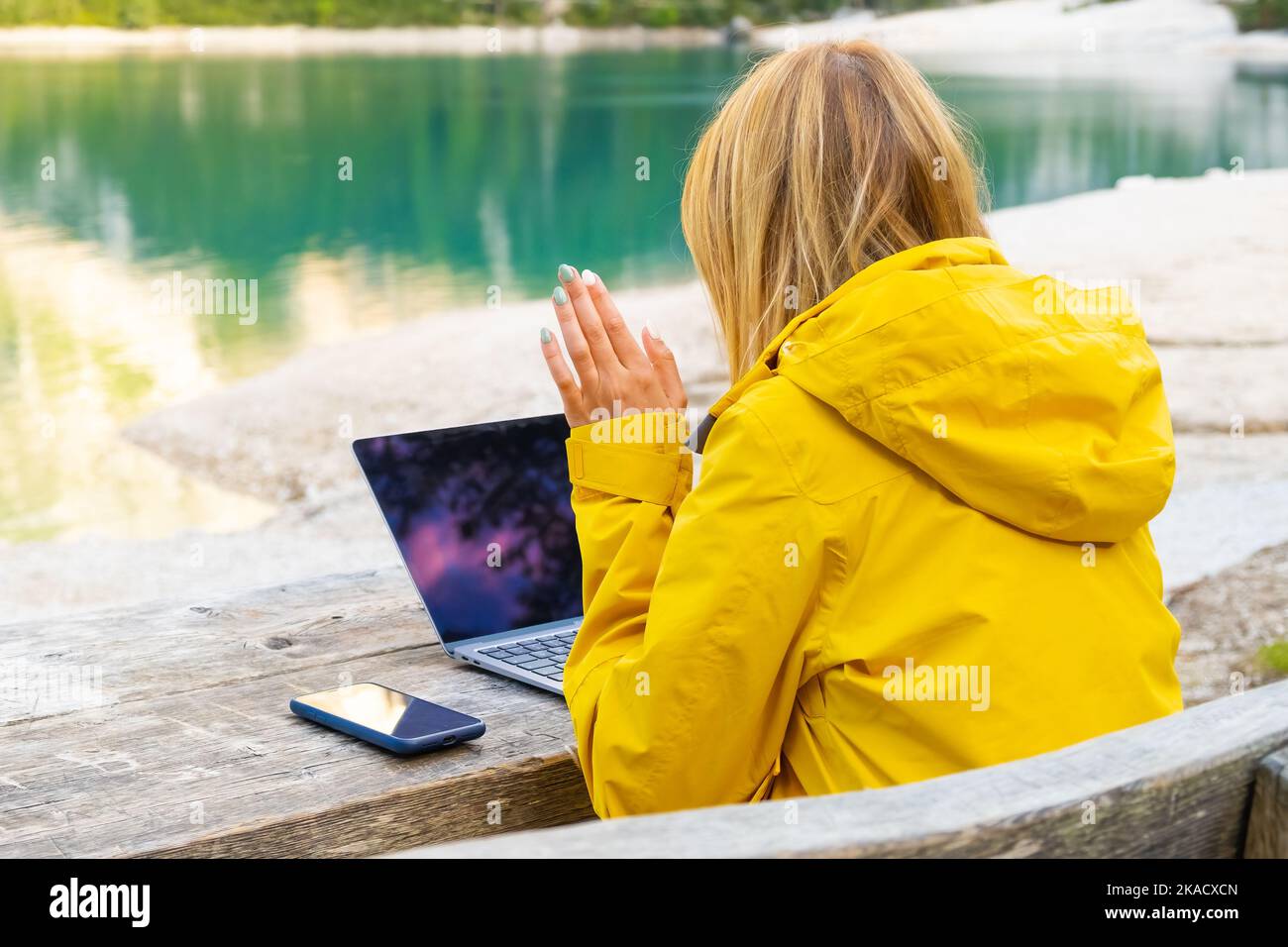 Freelancer having a video call near the lake. Young woman traveler ...