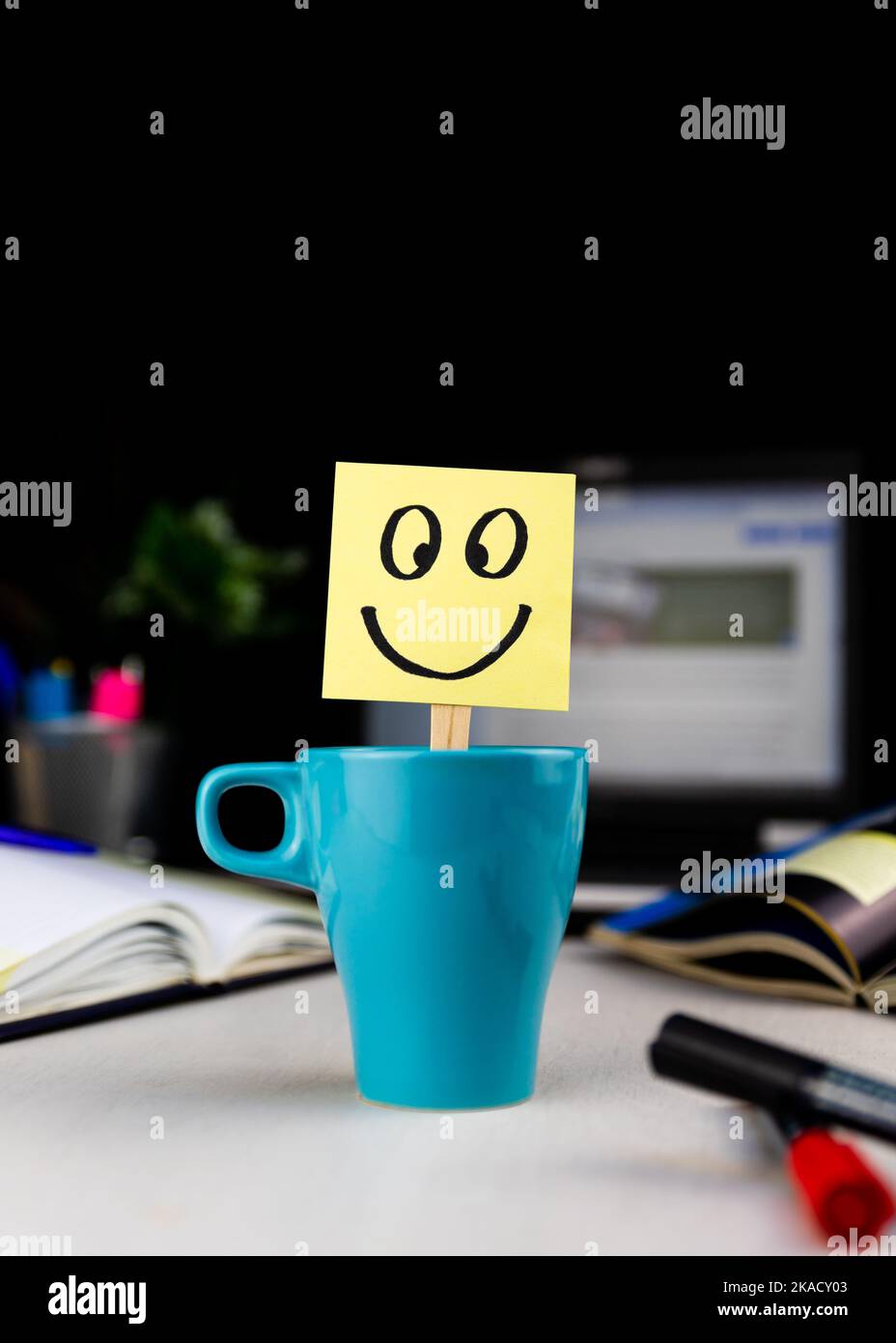 Smiling face drawn on sticky note inside a cup of coffee at the office ...