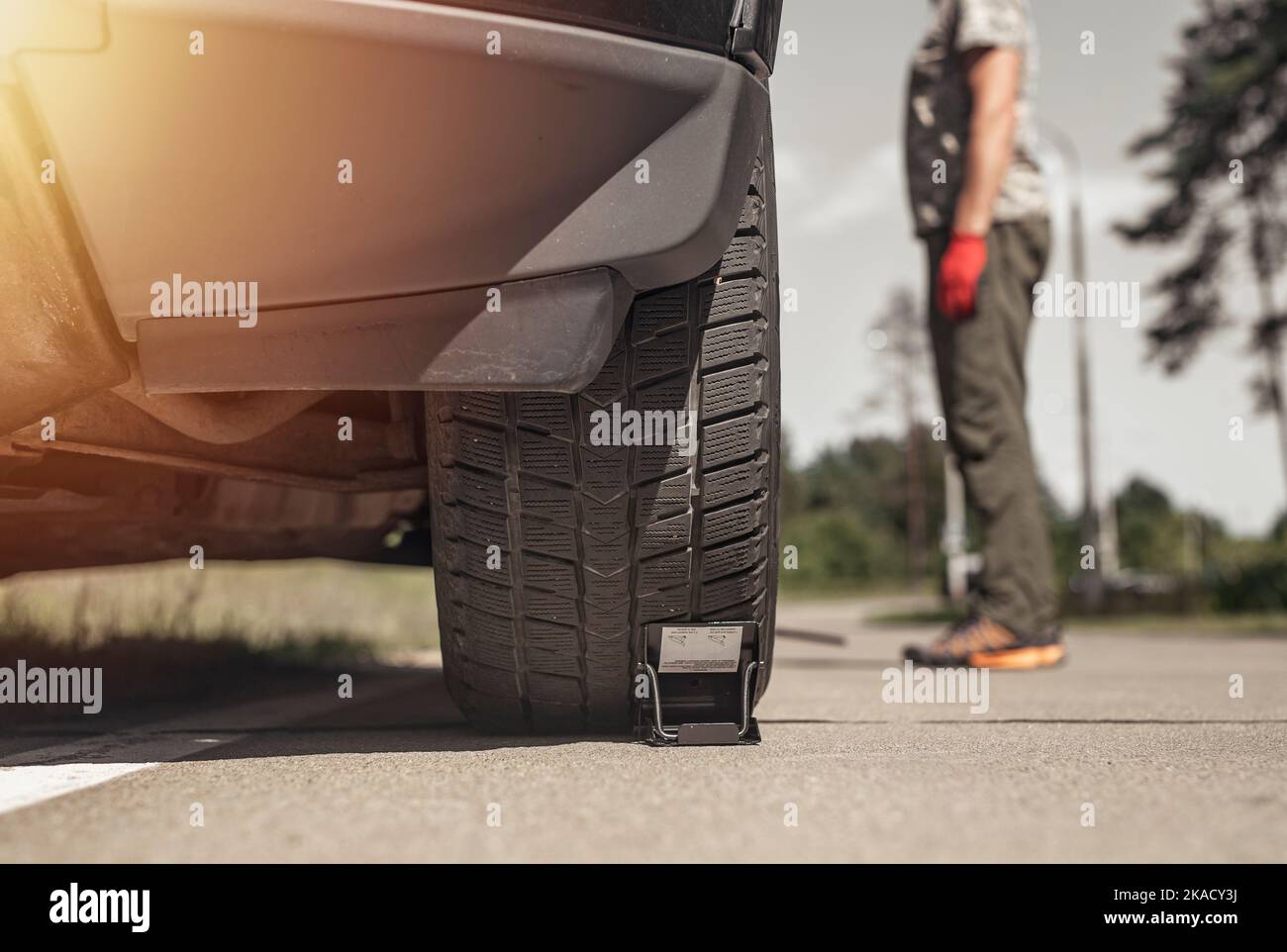 Wheel chocks under car tire on road, man standing nearby, bottom view ...