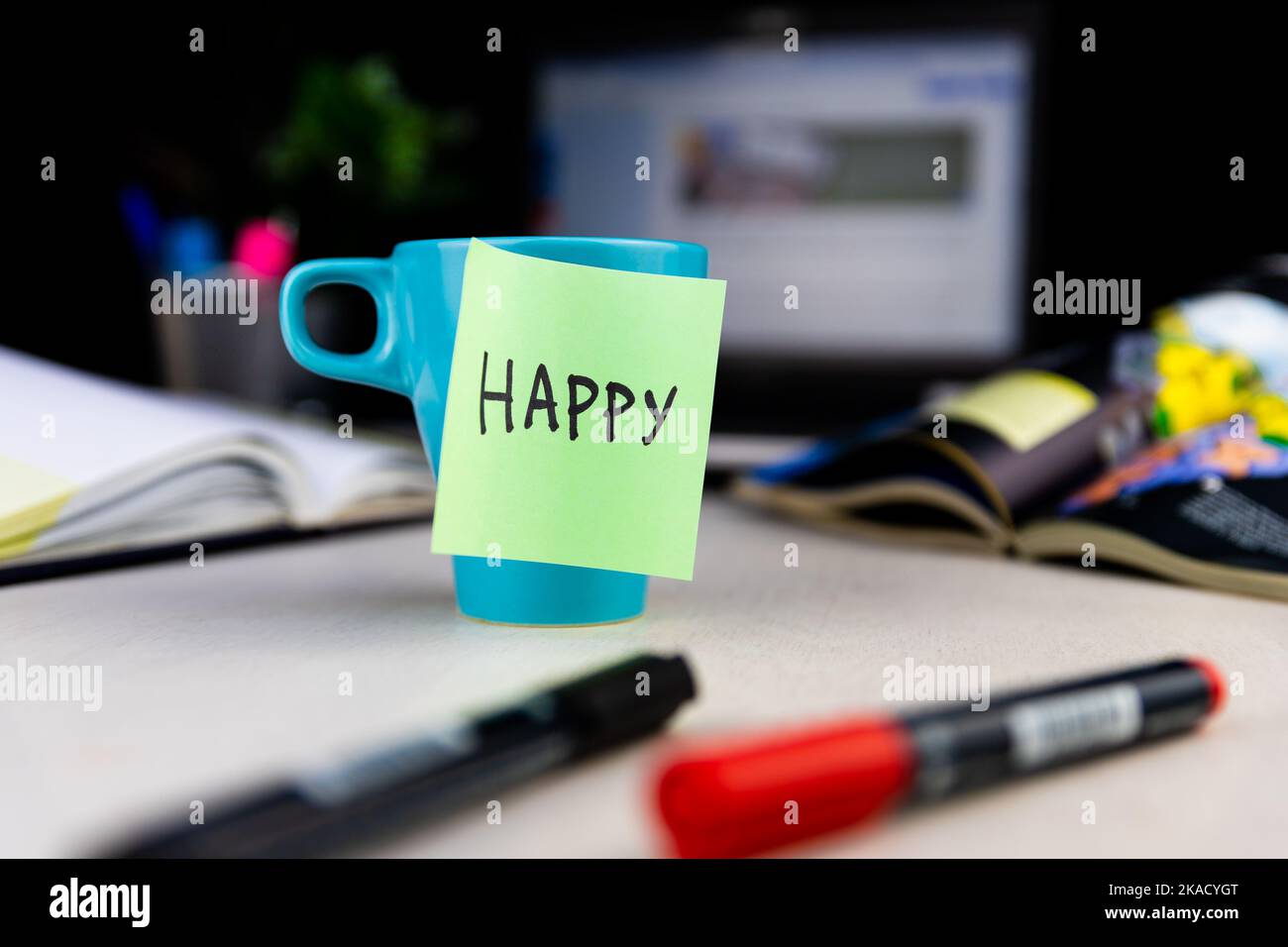 Sticky note with word Happy on a cup of coffee at the office desk ...