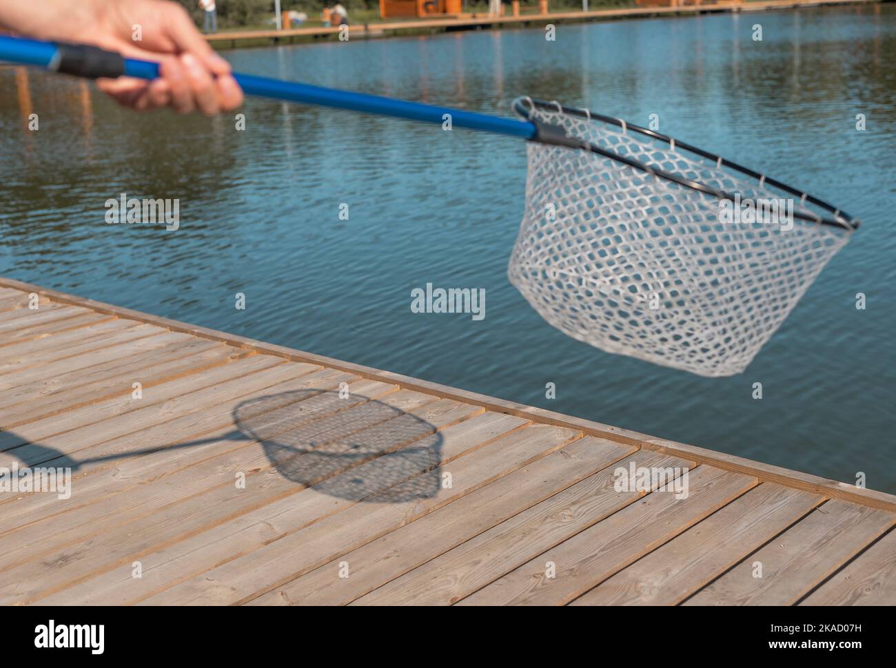 Hands holding fishing landing net with shadow on wood jetty Stock Photo ...