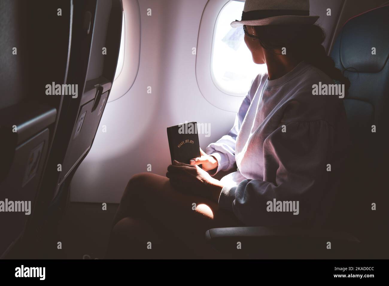 Woman looks out the window of an flying airplane. Young caucasian happy ...