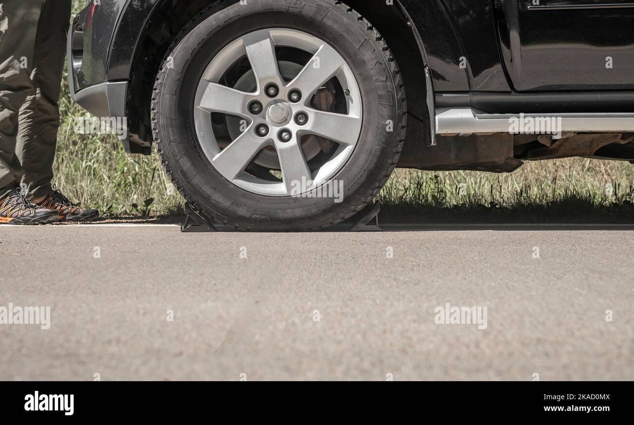 Wheel chocks under car tire on road, bottom view Stock Photo - Alamy