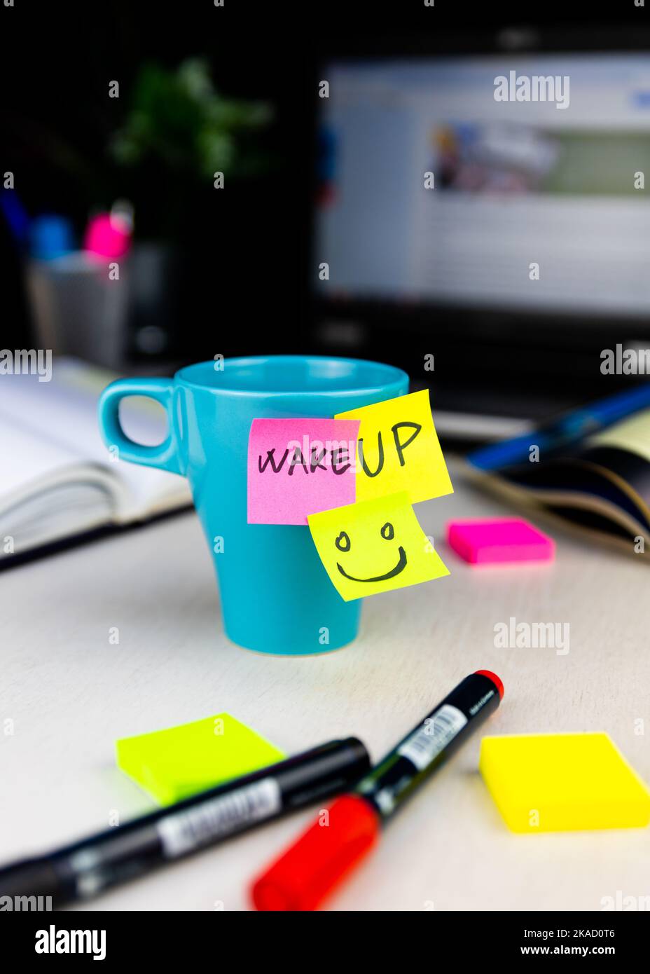 Sticky notes on a coffe cup at office desk. Wake up and smile. Begin ...