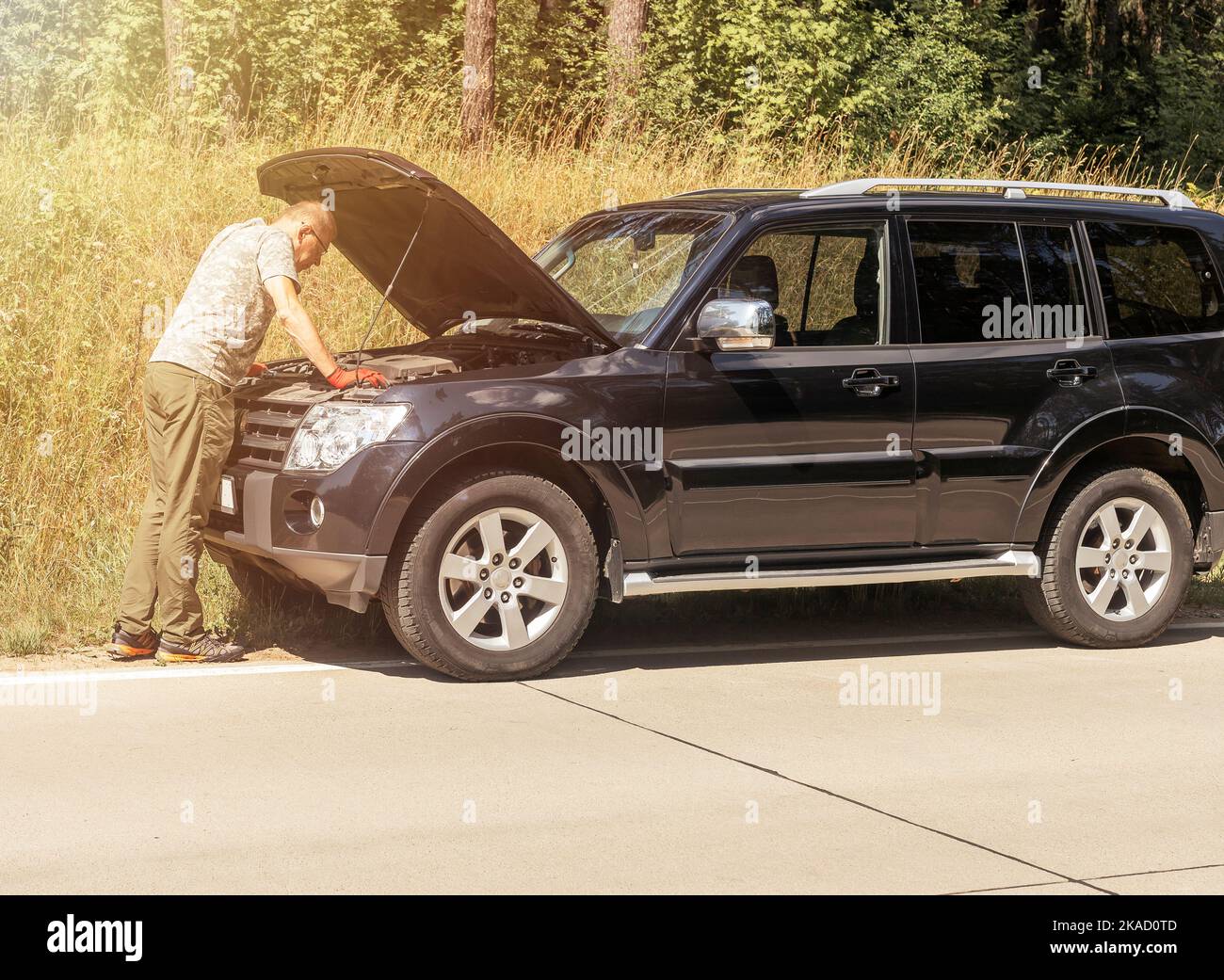 Driver standing near car hood raised up and checking, inspecting for ...