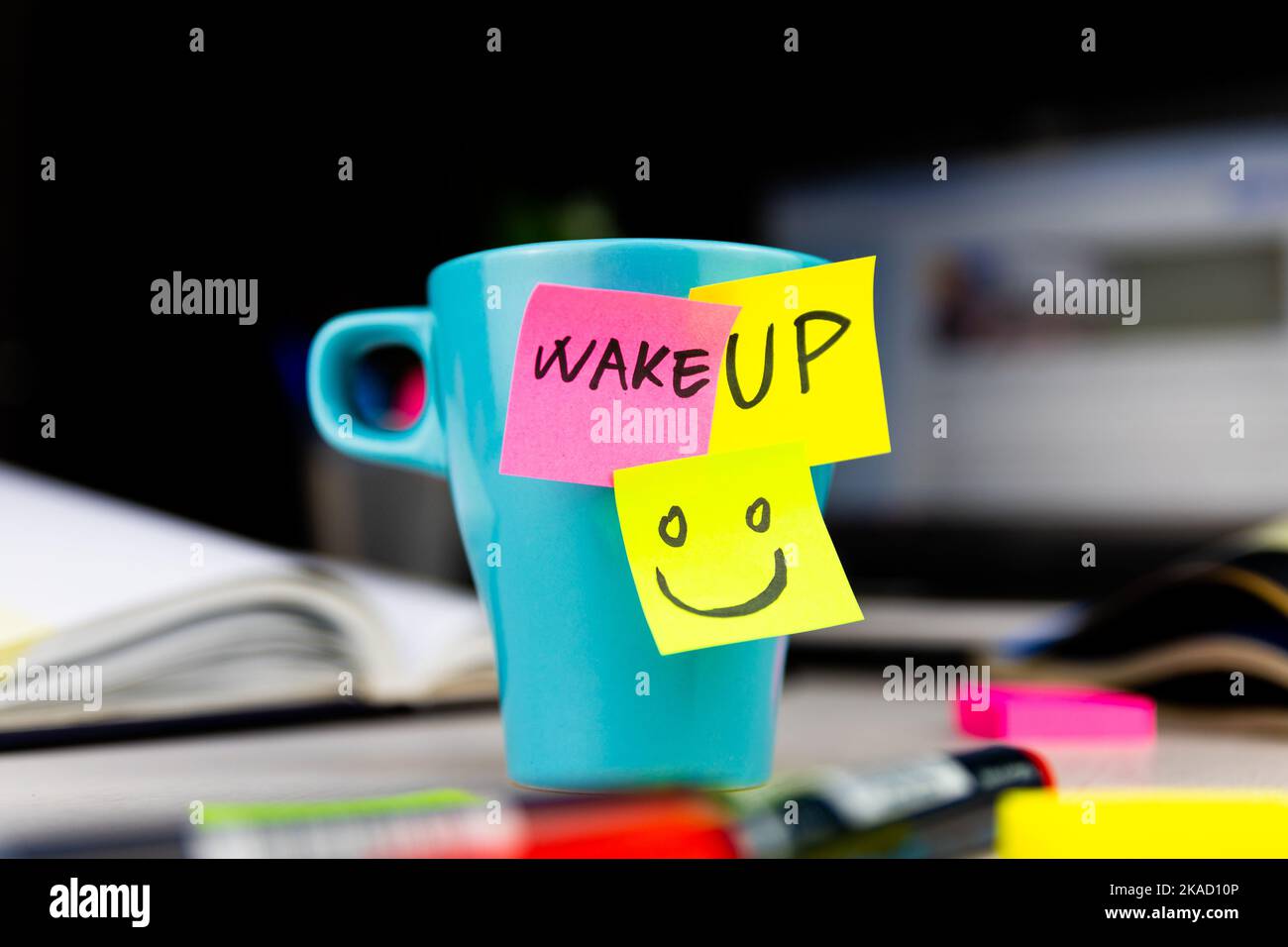 Sticky notes on a coffe cup at office desk. Wake up and smile. Begin ...