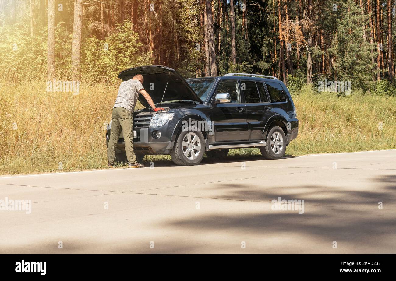 Man driver standing near car with hood raised up and checking for ...