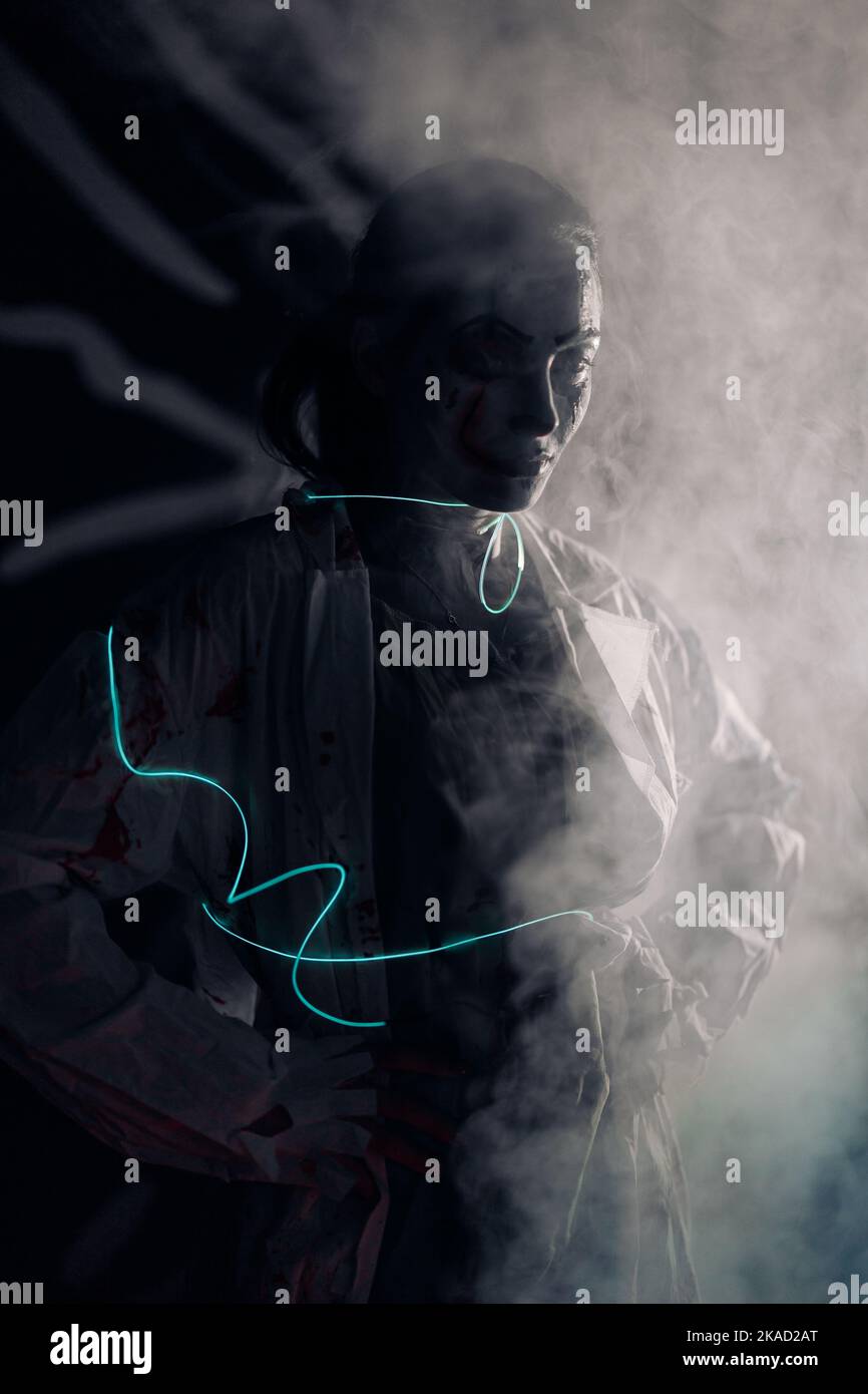 Young woman with glowing blue led band portrays bloodthirsty zombie ...