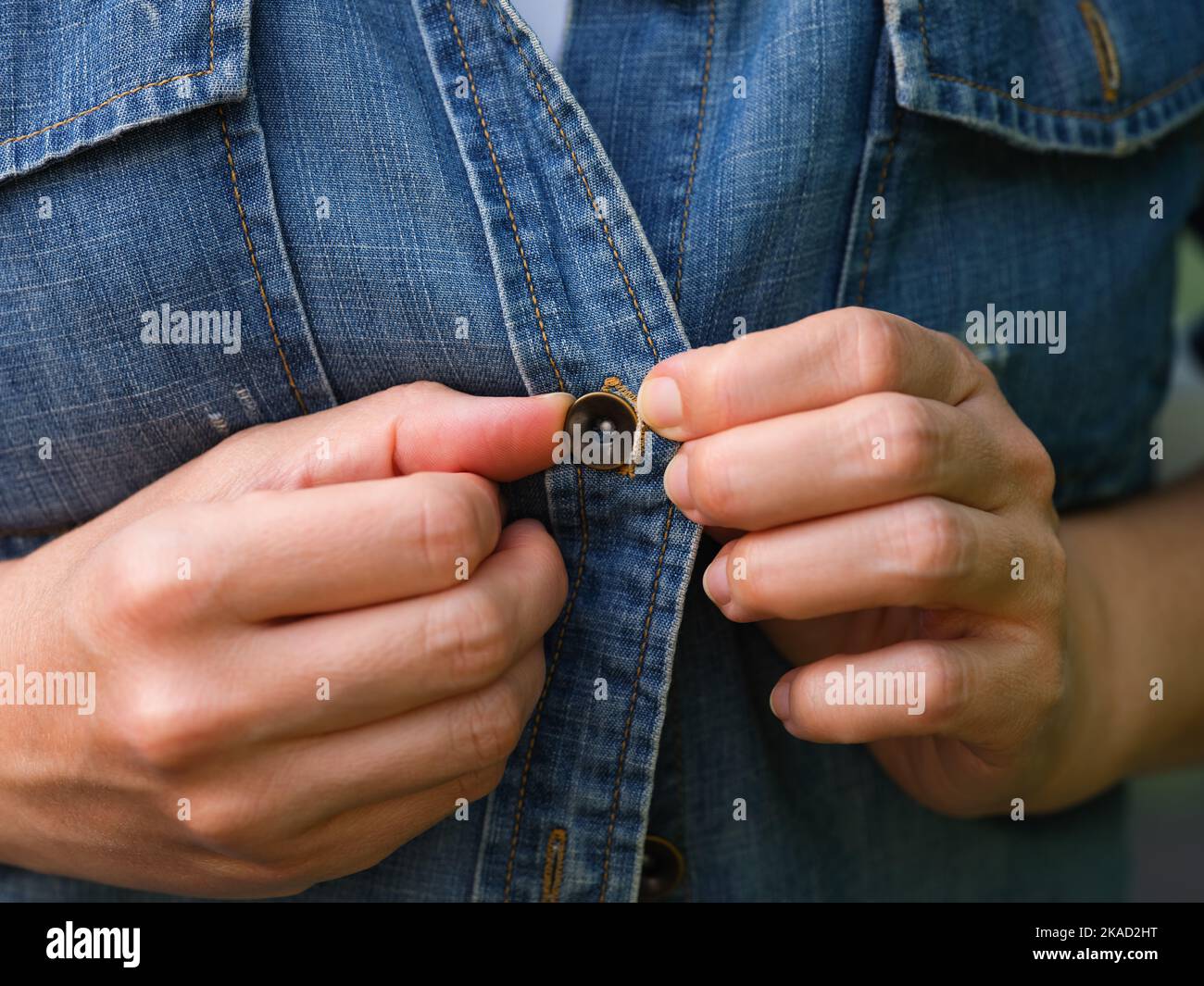 A woman buttoning a denim jacket. Close-up Stock Photo - Alamy