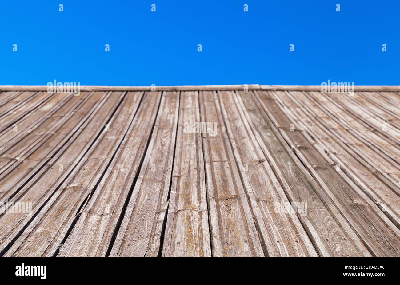 Gray wooden roof slope is under blue sky, perspective view with ...