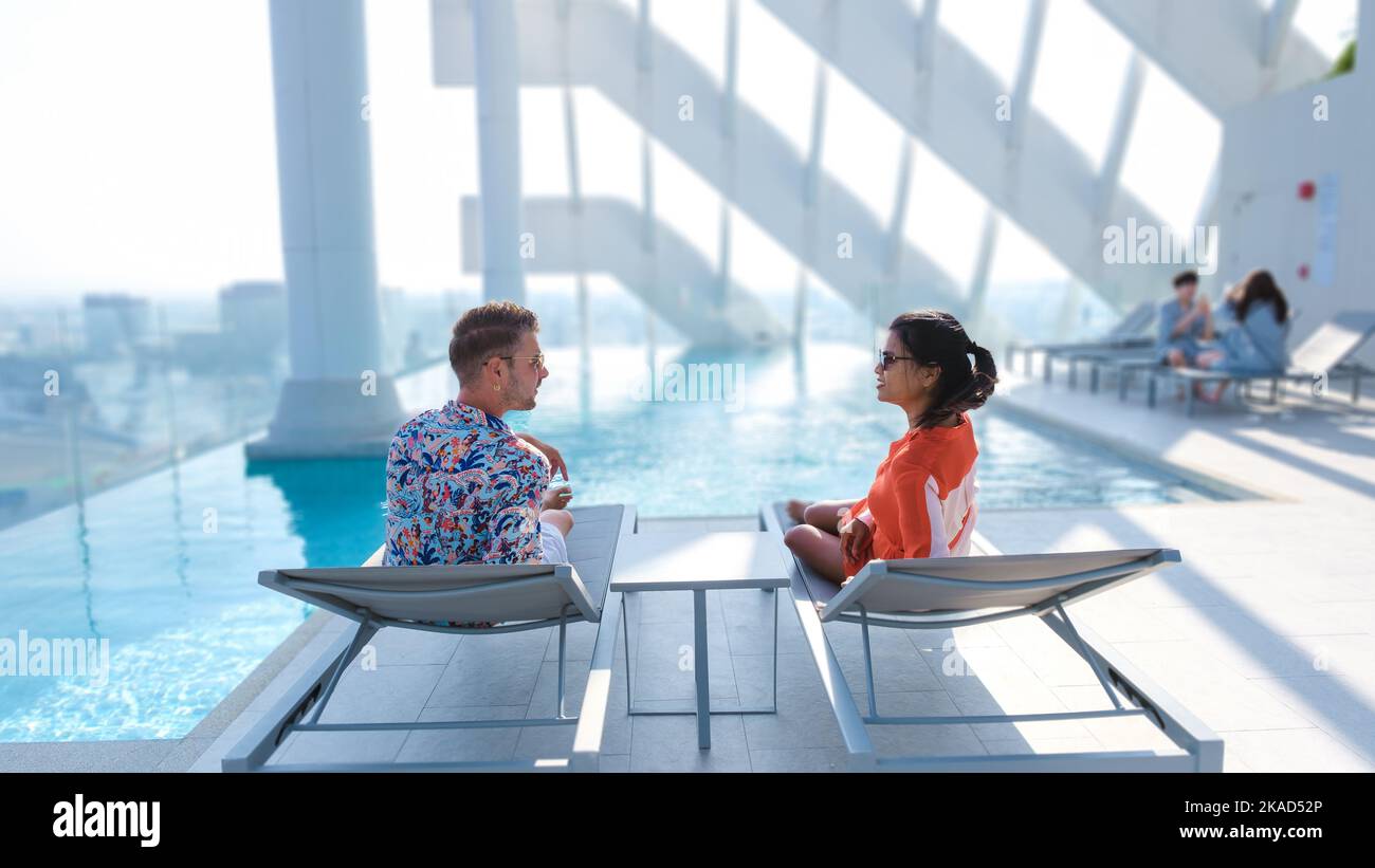 couple of men and women relaxing at a rooftop pool of a luxury hotel ...