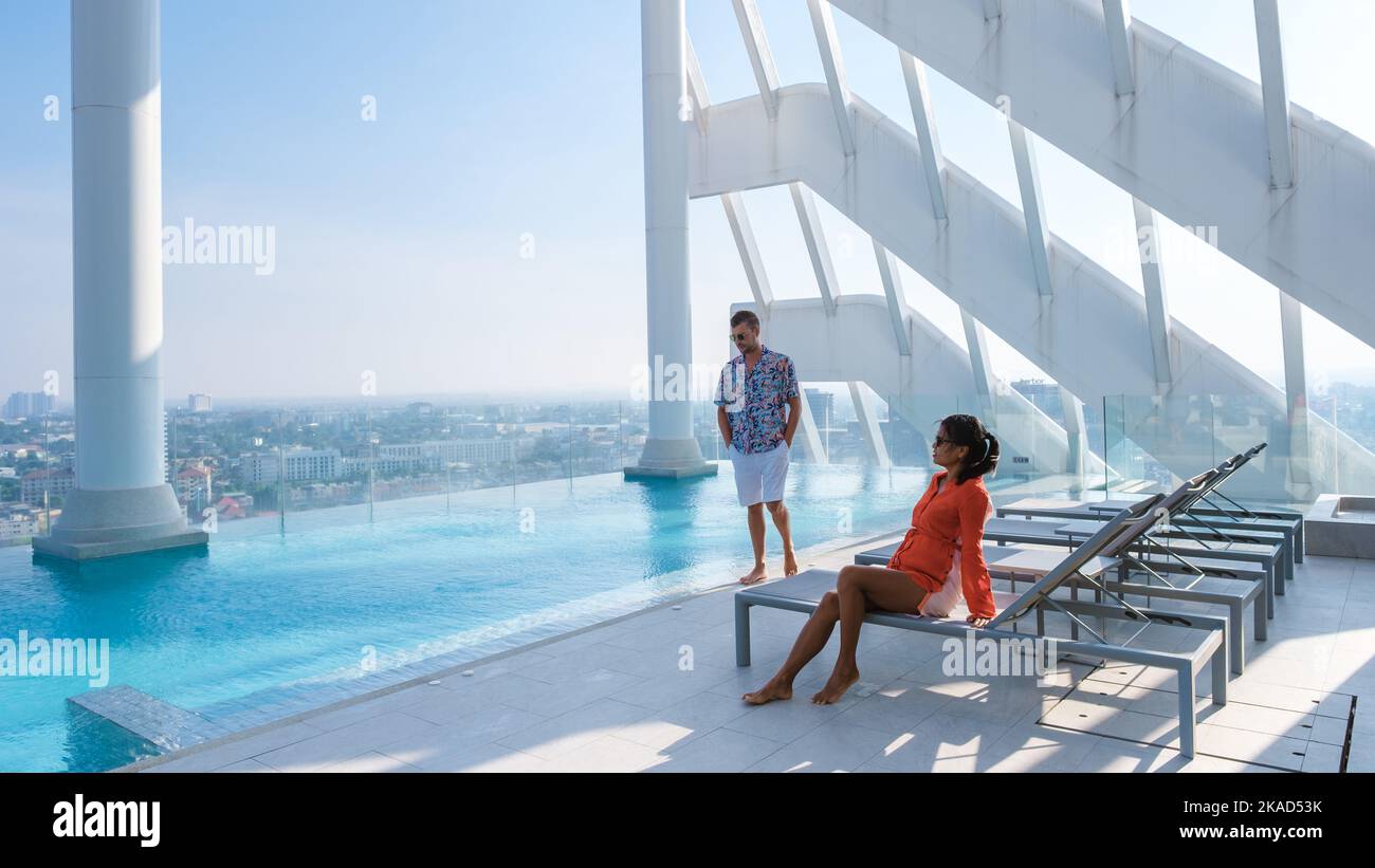 couple of men and women relaxing at a rooftop pool of a luxury hotel ...