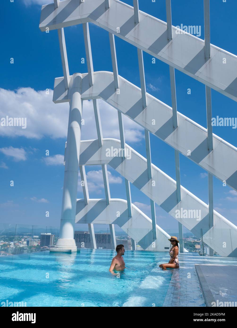 Thai women and European men visit a rooftop pool during vacation ...