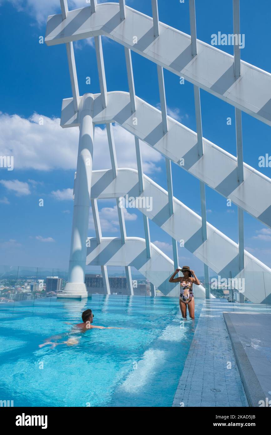 Thai women and European men visit a rooftop pool during vacation ...