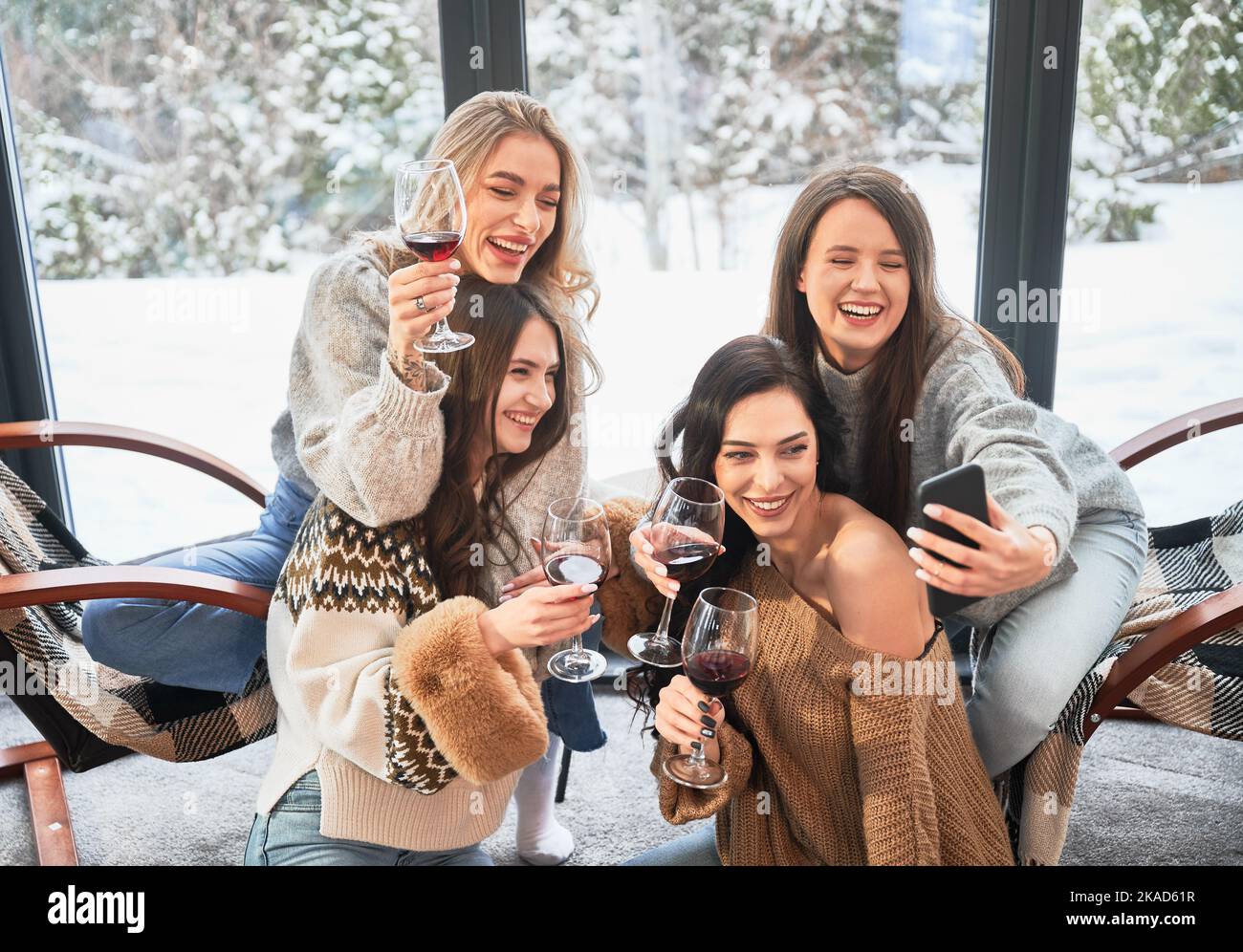 Young women enjoying winter weekends inside contemporary barn house. Four girls having fun ...