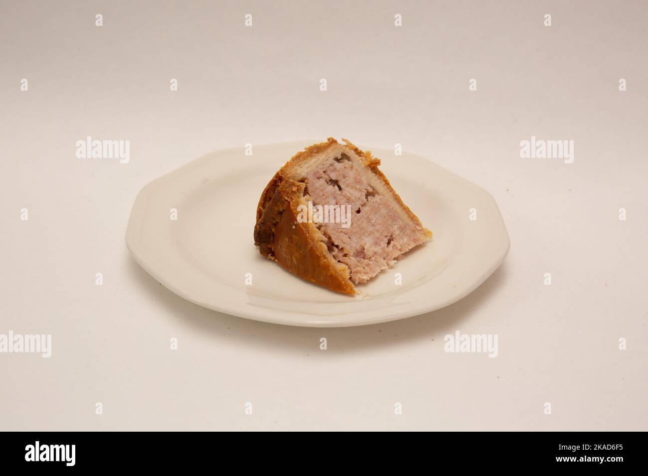 Tasty British crusty pork pie slice cut ready to eat on plate isolated ...
