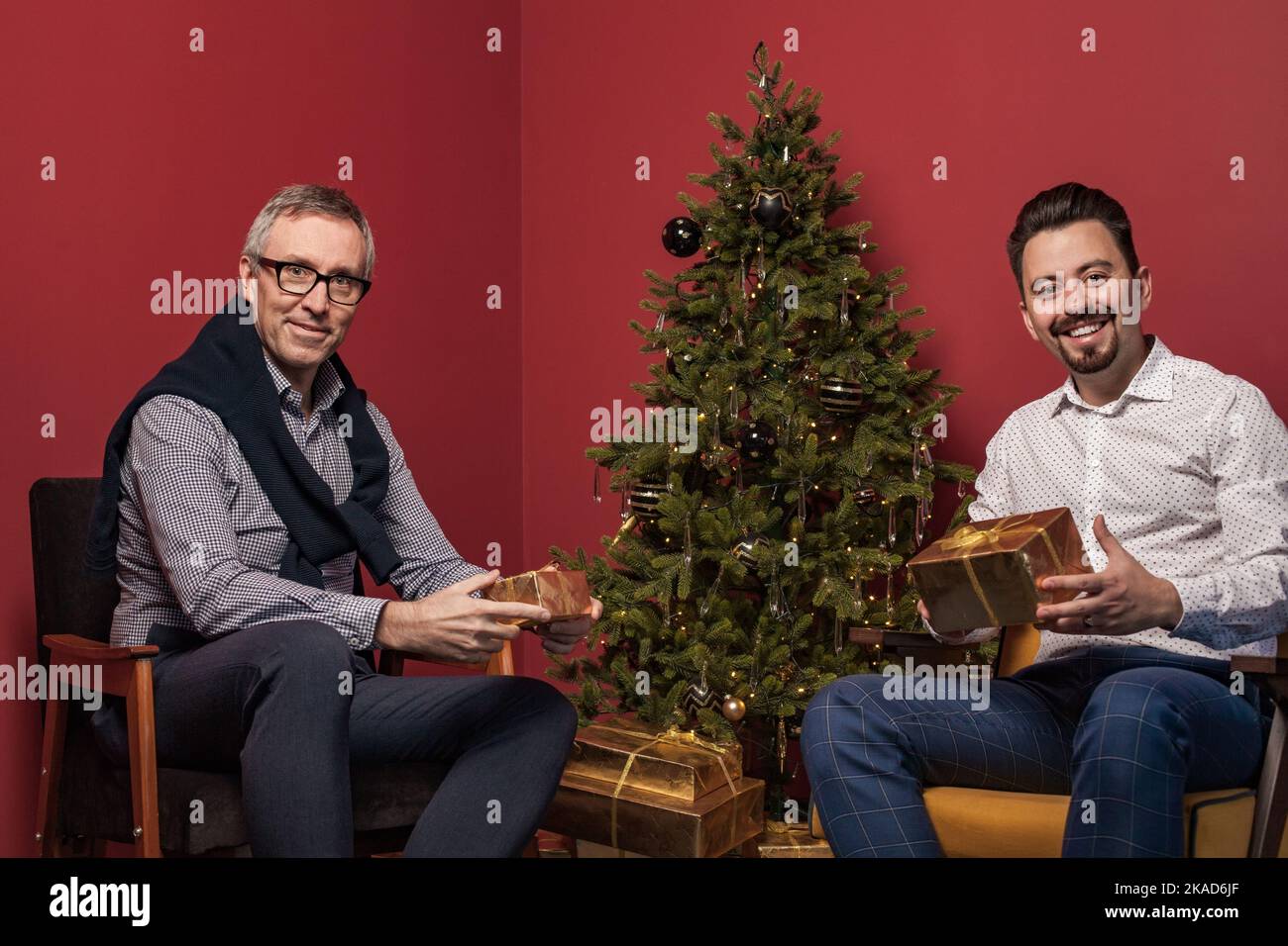 Elderly man and his son smiling and showing Christmas presents gold ...