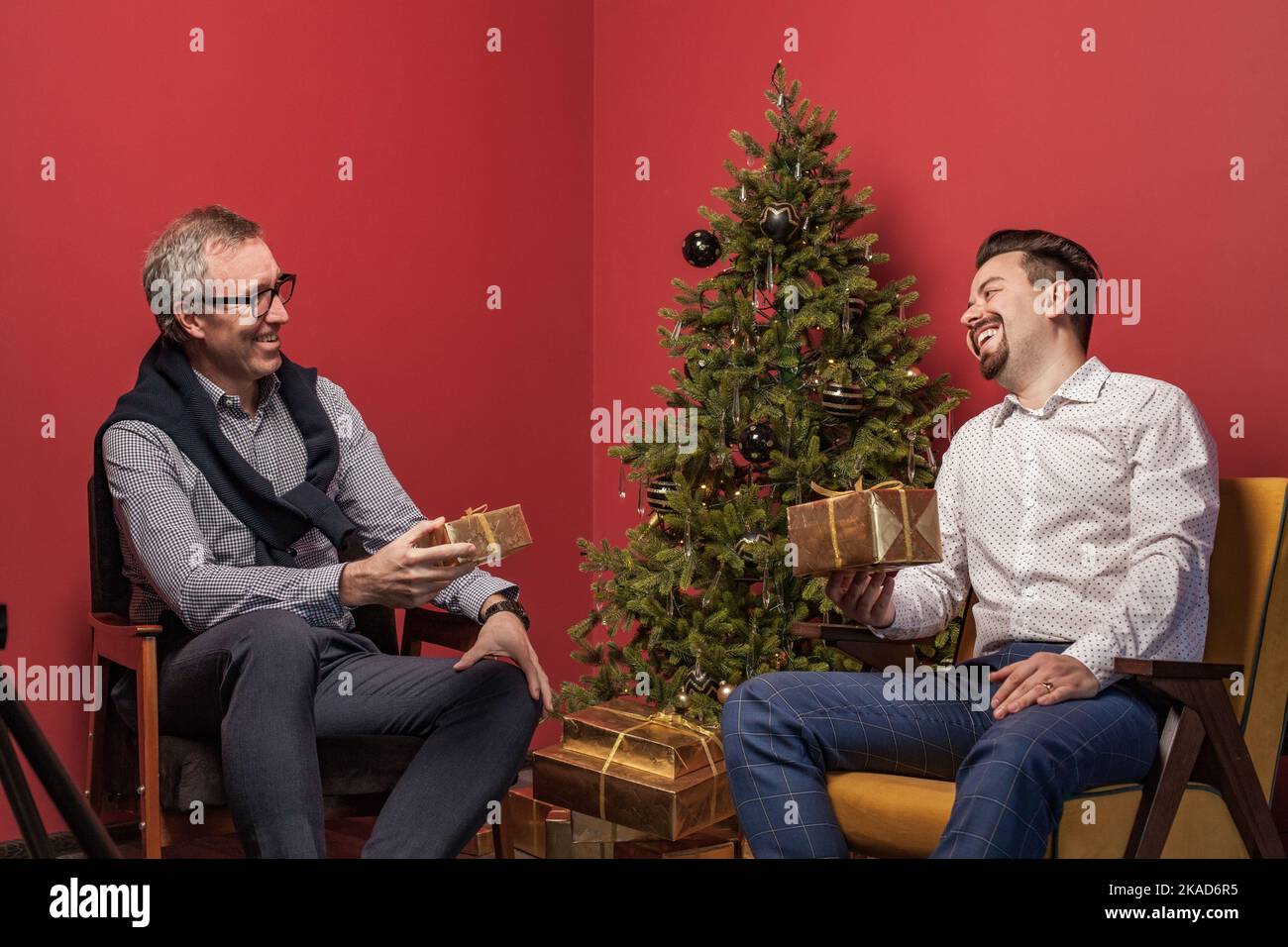 Elderly man and his son laughing and exchanging Christmas presents on ...