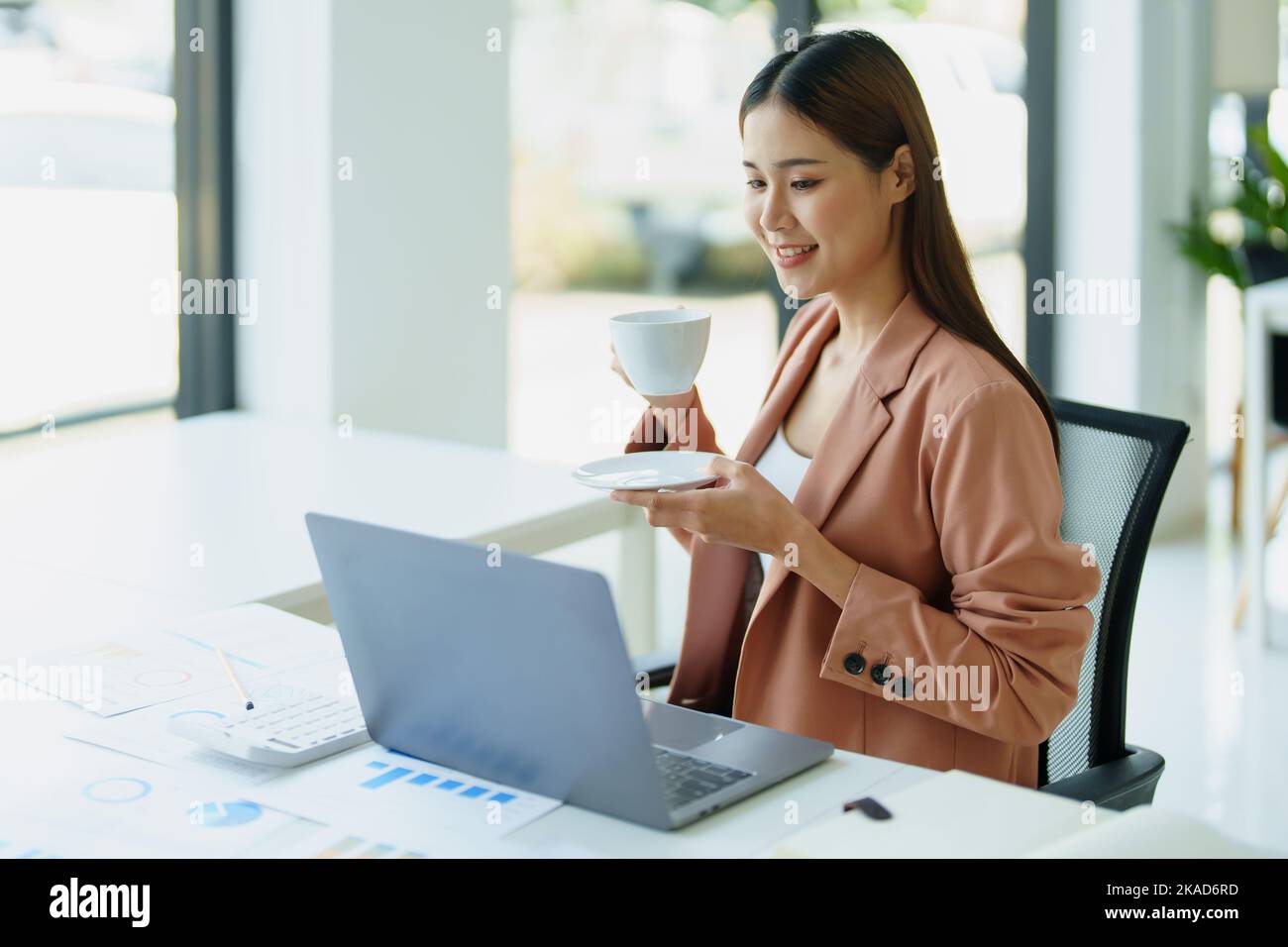 Portrait of a woman taking a coffee break while using a computer Stock ...