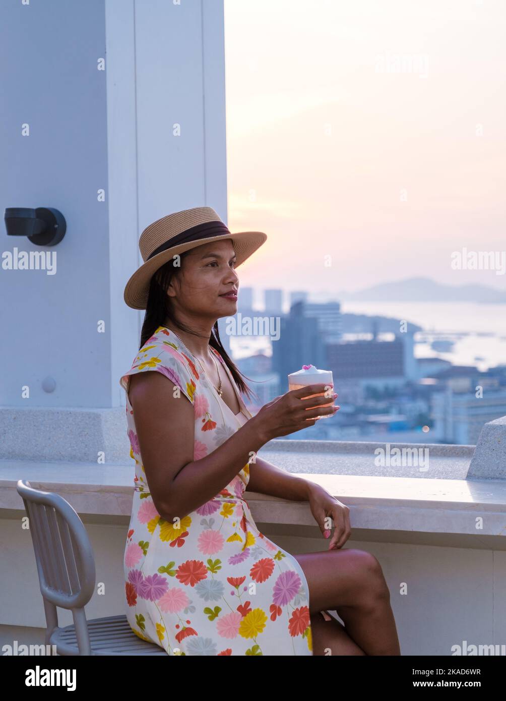 young women having a drink on a rooftop bar looking out over the city ...
