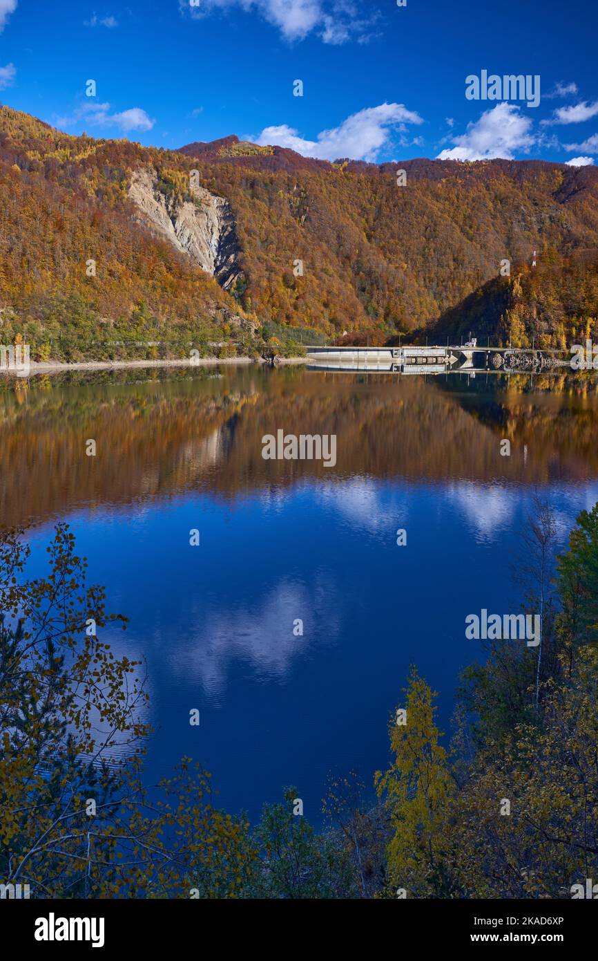Colorful forests on mountains surrounding a dam lake with reflection in ...