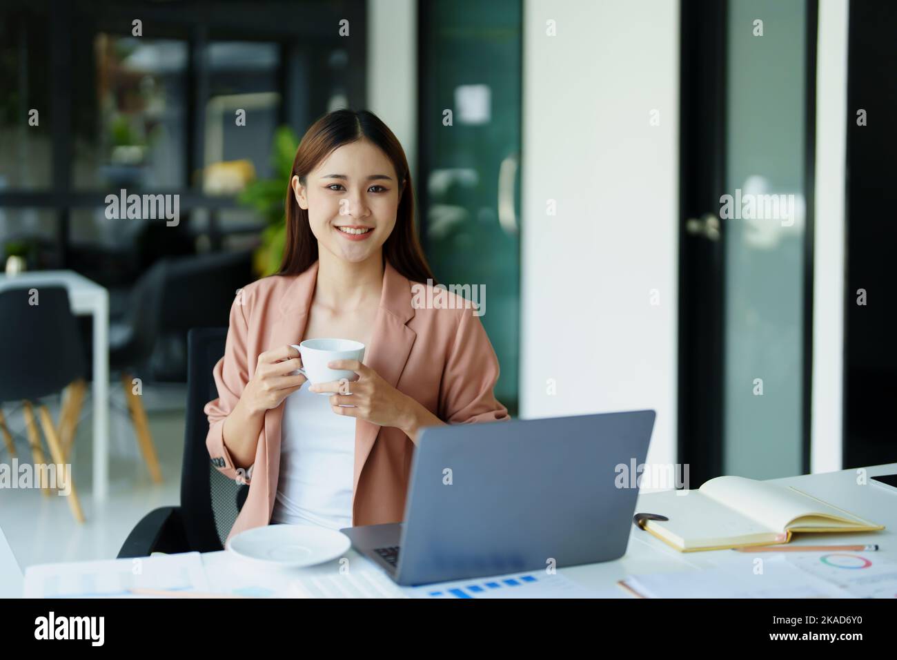 Portrait of a woman taking a coffee break while using a computer Stock ...